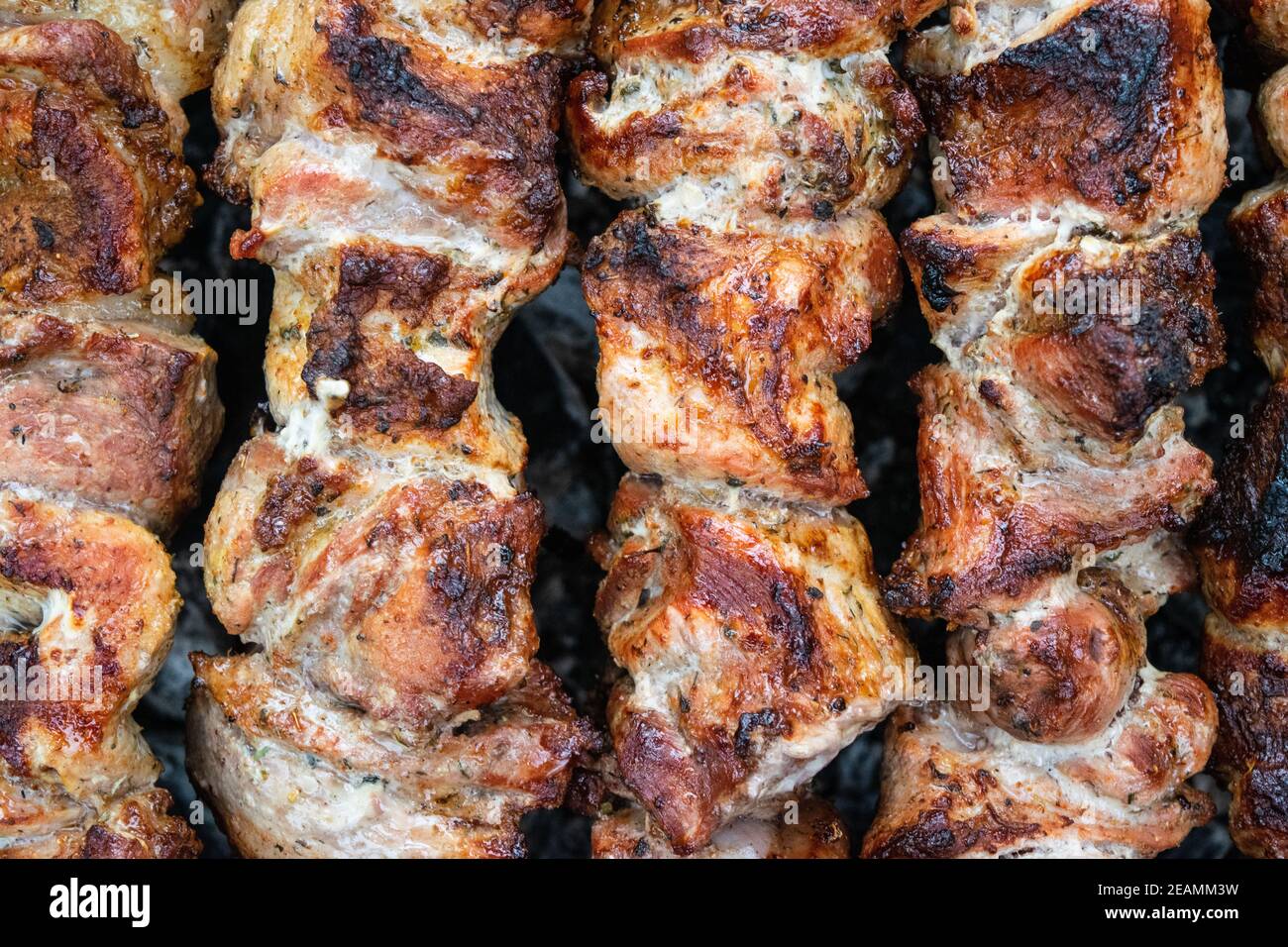 Frying pork on a skewer over a brazier. Turning meat over coals ...