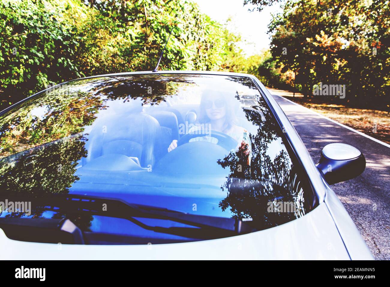 Woman driving convertible car in nature. Looking through windshield ...