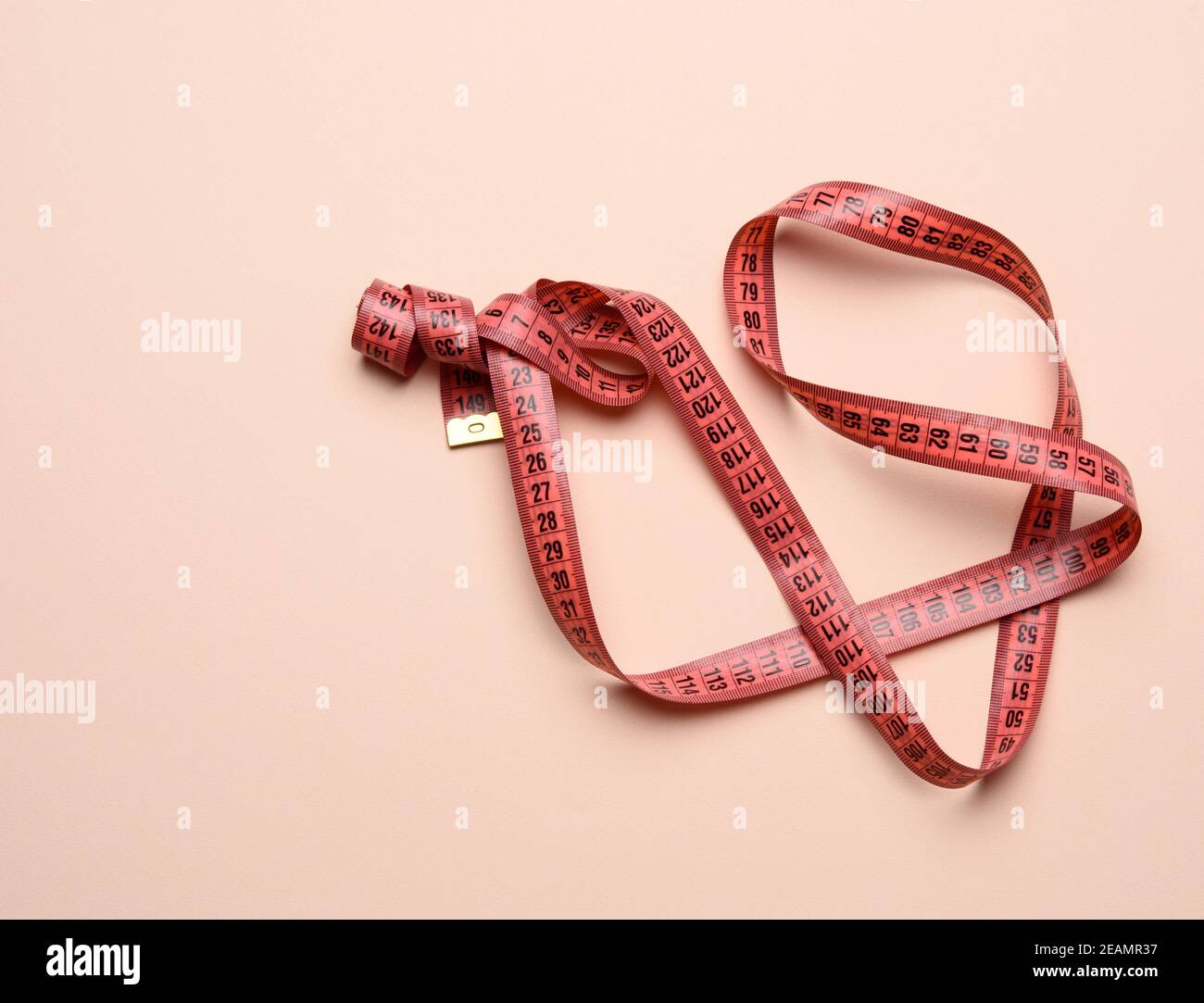 twisted white measuring tape on a beige background Stock Photo - Alamy