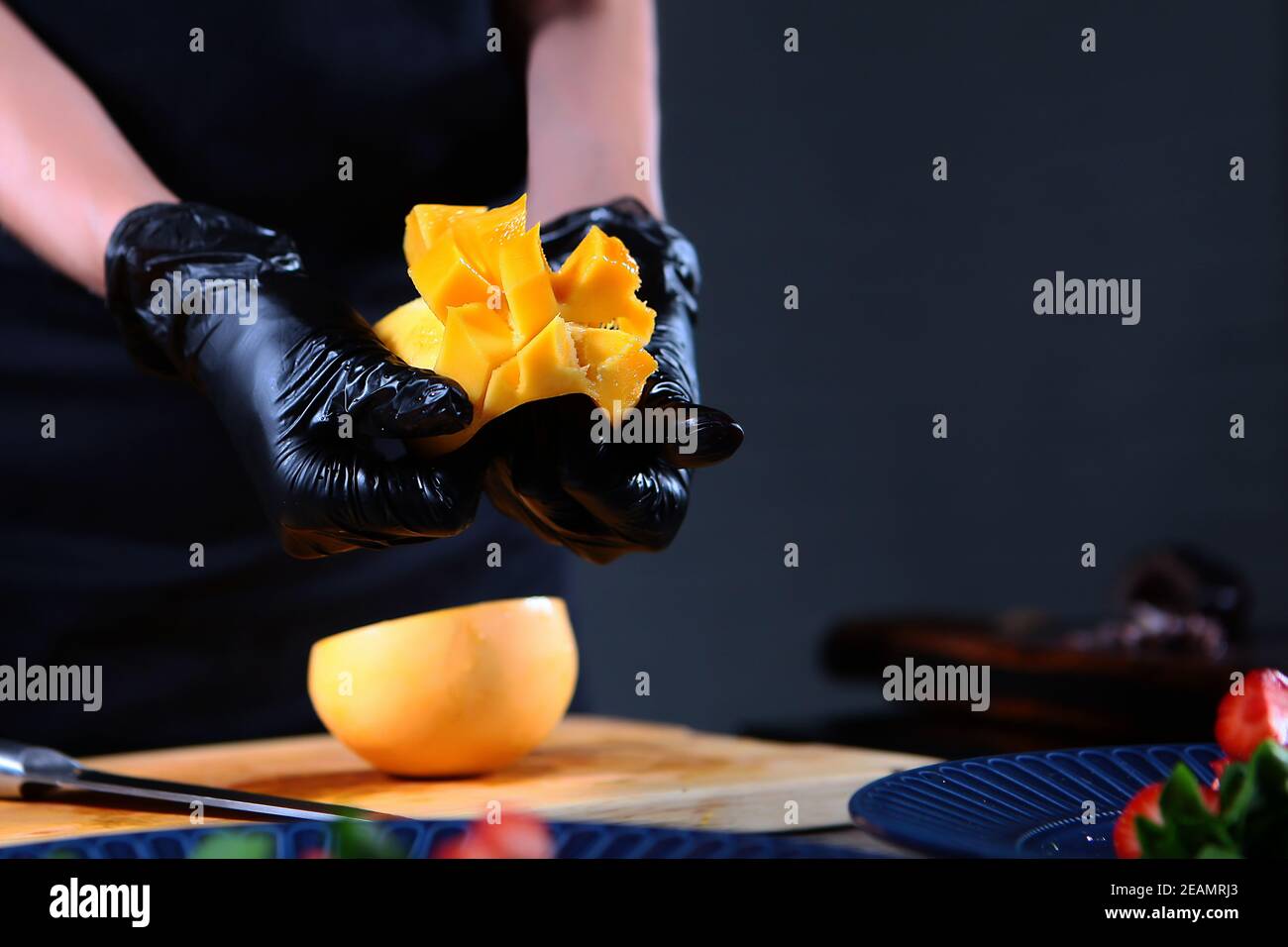 Ripe mango in the hands of the chef. The chef cuts mango. Preparation ...