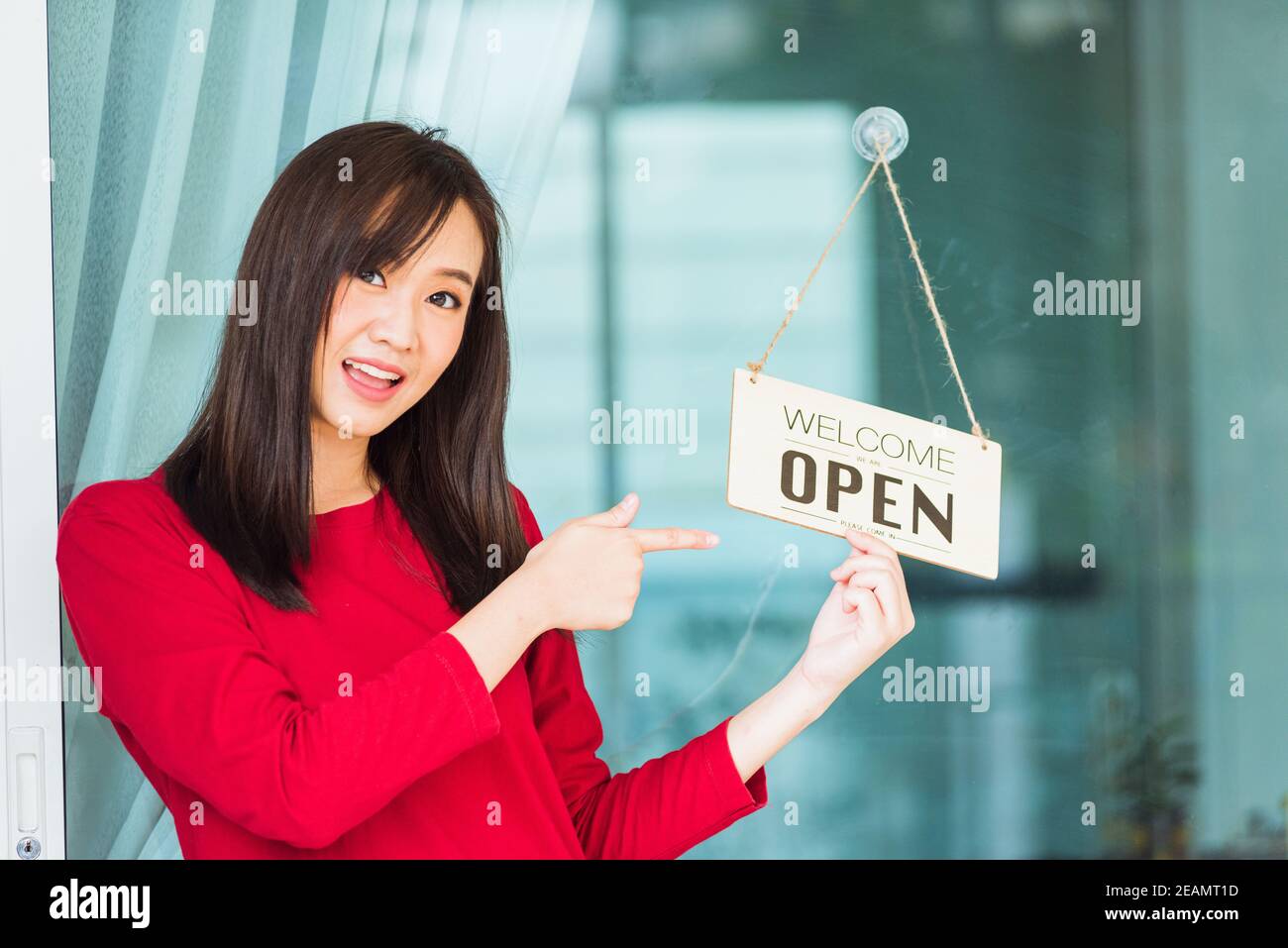 Woman smiling point finger to notice sign wood board label "WELCOME ...