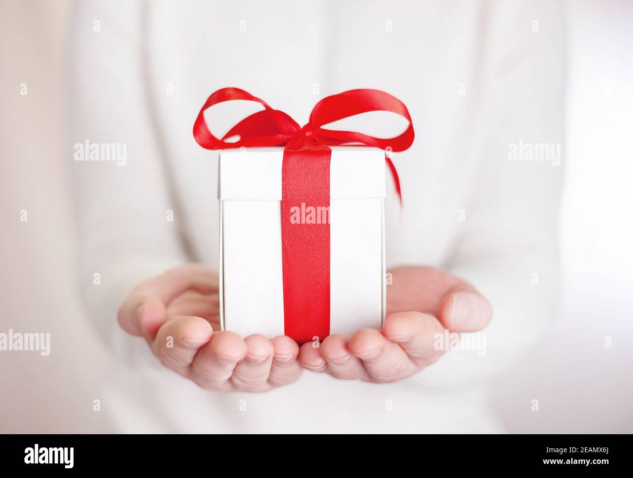 Woman holding a gift box in a gesture of giving Stock Photo - Alamy