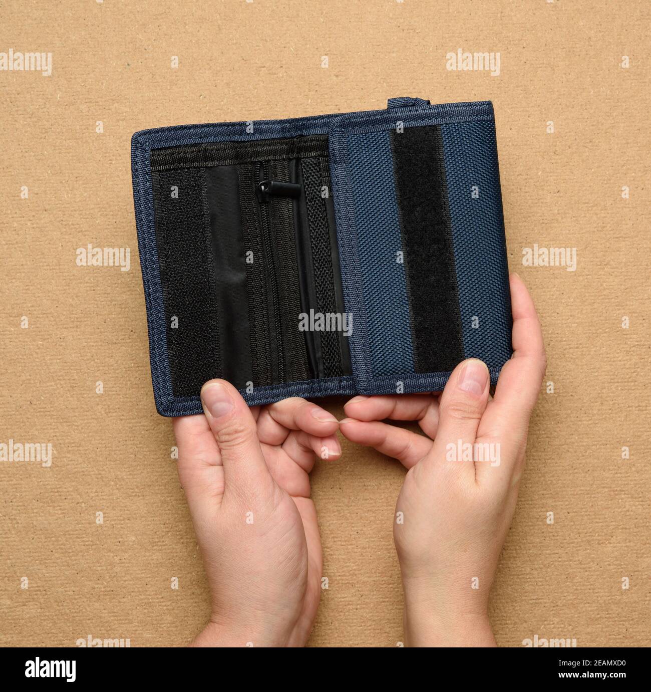 female hands hold open empty blue textile wallet on brown background ...