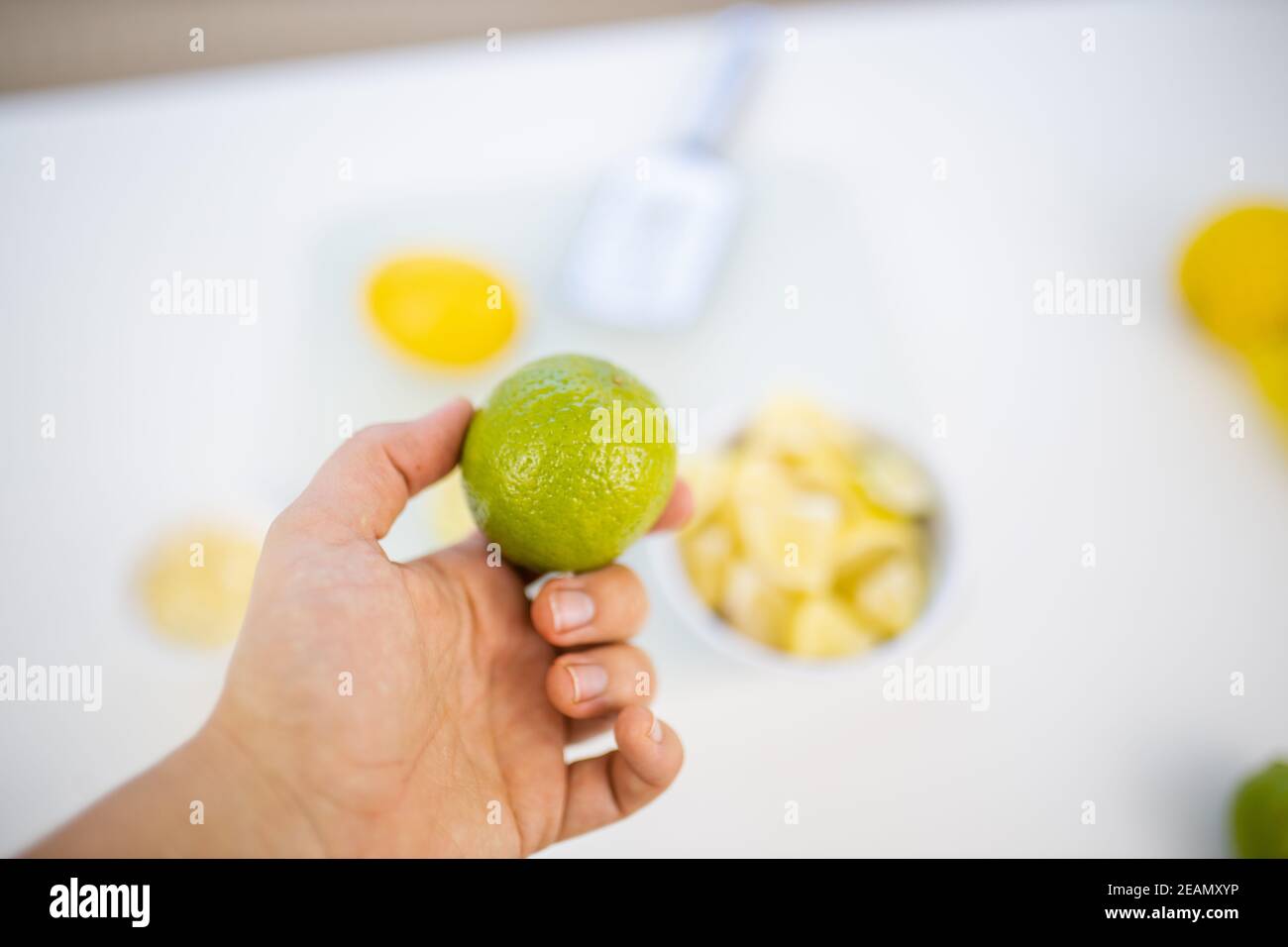 Female hand holding a lime above slices of limes and lemons Stock Photo ...
