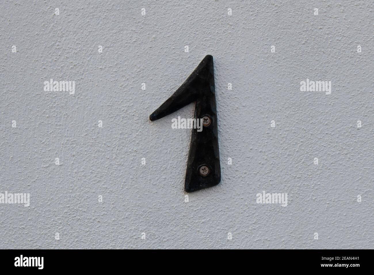 The number 1 carved in wood, painted black and screwed to a white rough ...