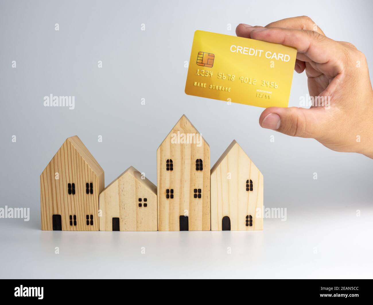 Model wooden house and hand of person holding credit card On a white ...