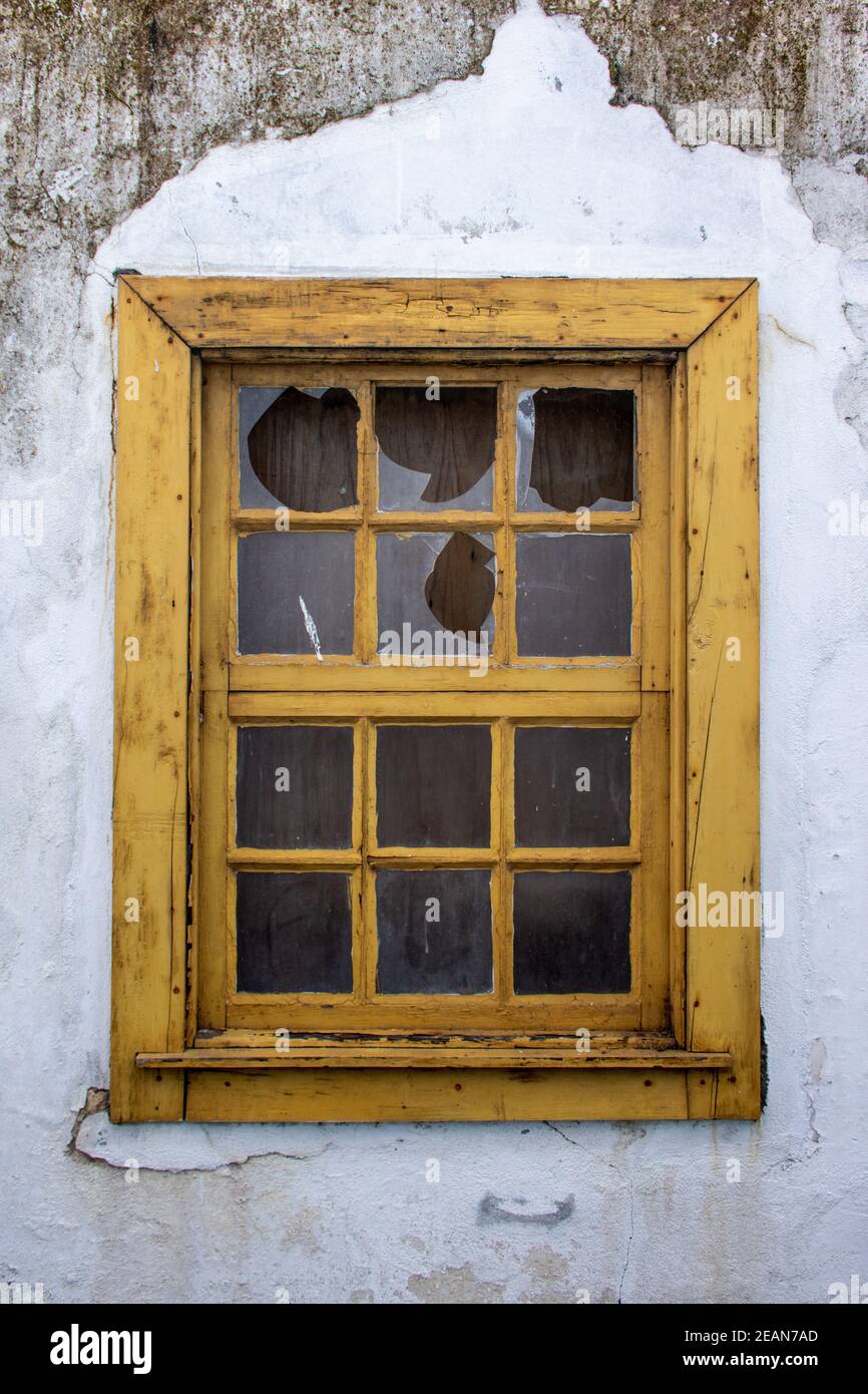 Vandalized old yellow wooden window with broken glass and dirty damaged ...