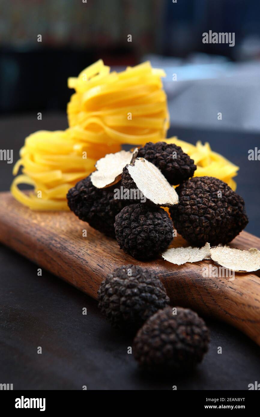 Black truffle on a wooden Board with paste in the form of nests. The ...