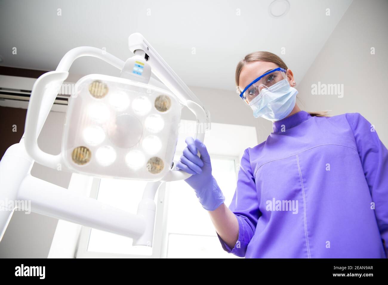 The dentist directs the lighting device at the client Stock Photo - Alamy