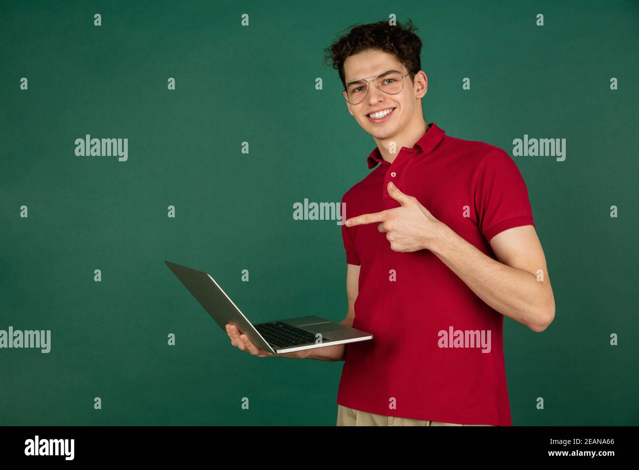 Pointing on screen. Caucasian handsome man's portrait isolated on green ...