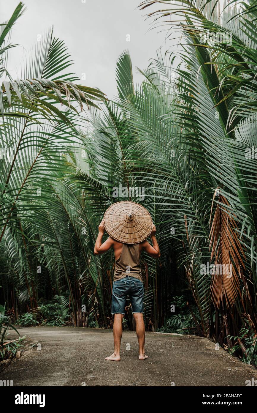 A guy on a path in the tropics, in a hat and t-shirt Stock Photo - Alamy