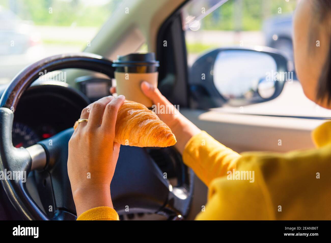 woman eating food fastfood and drink coffee while driving the car Stock ...