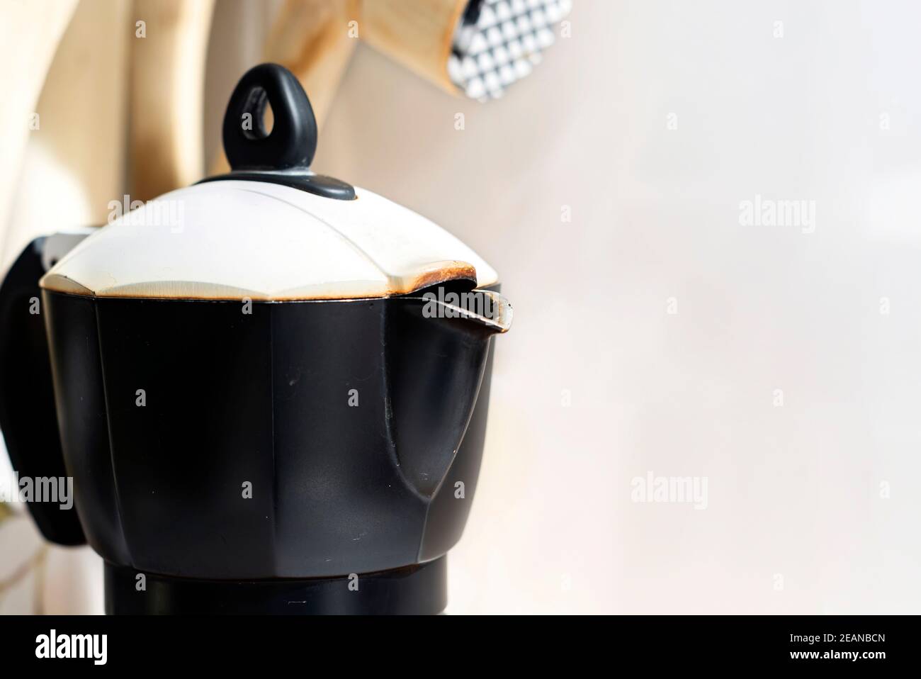 detail of the spout of the black coffee pot with the white lid in a ...