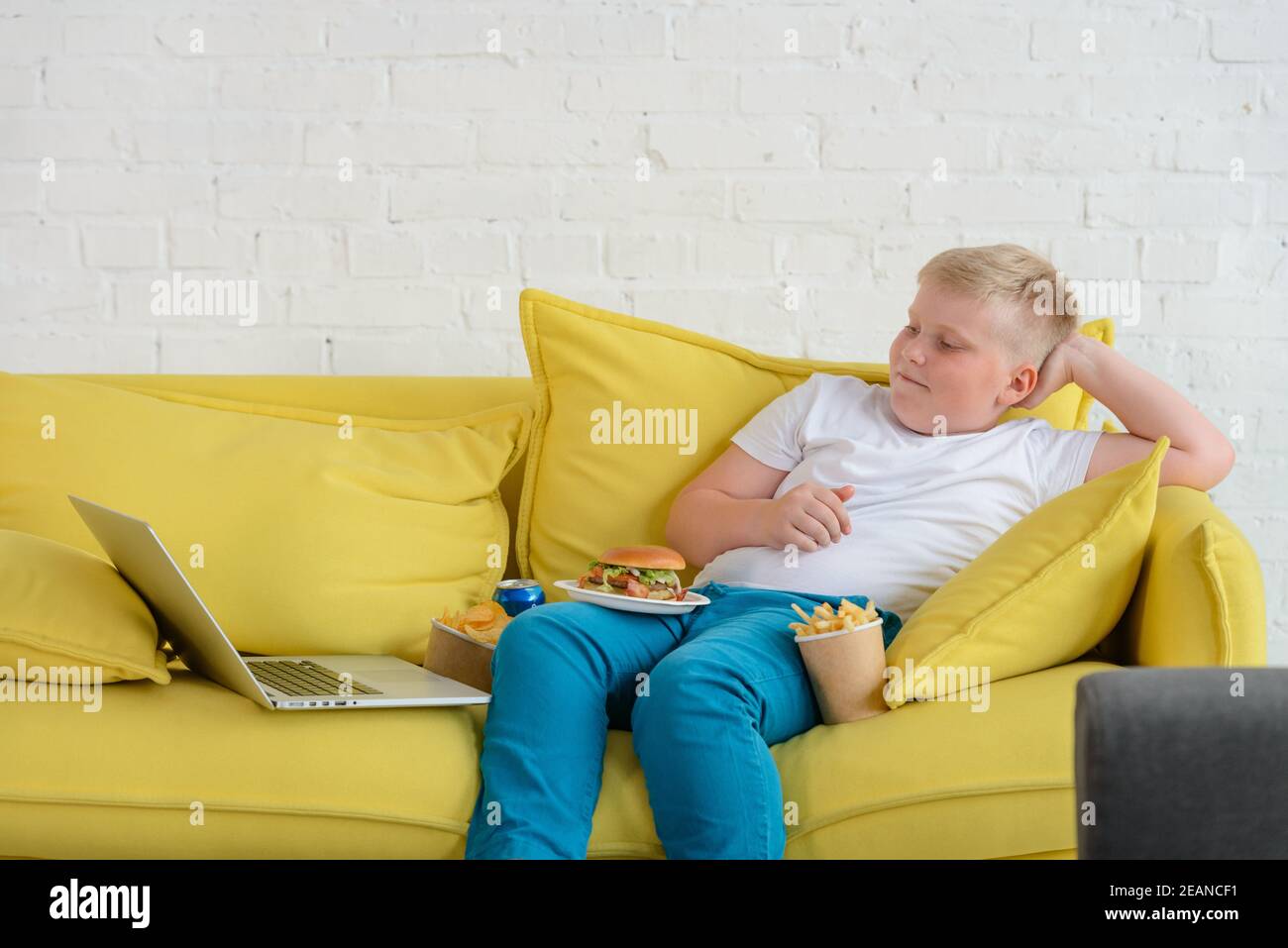 Lazy fat boy eating junk food and watching a movie Stock Photo - Alamy