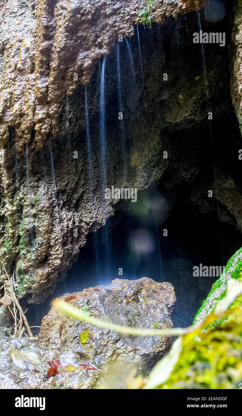 Water flows through rocks in the cave. A small waterfall at the ...