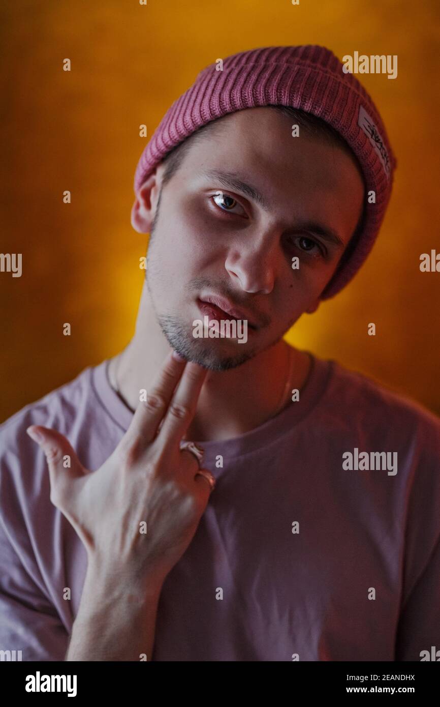 Portrait of a cheeky guy, in a knitted pink hat, shows a gesture Stock ...