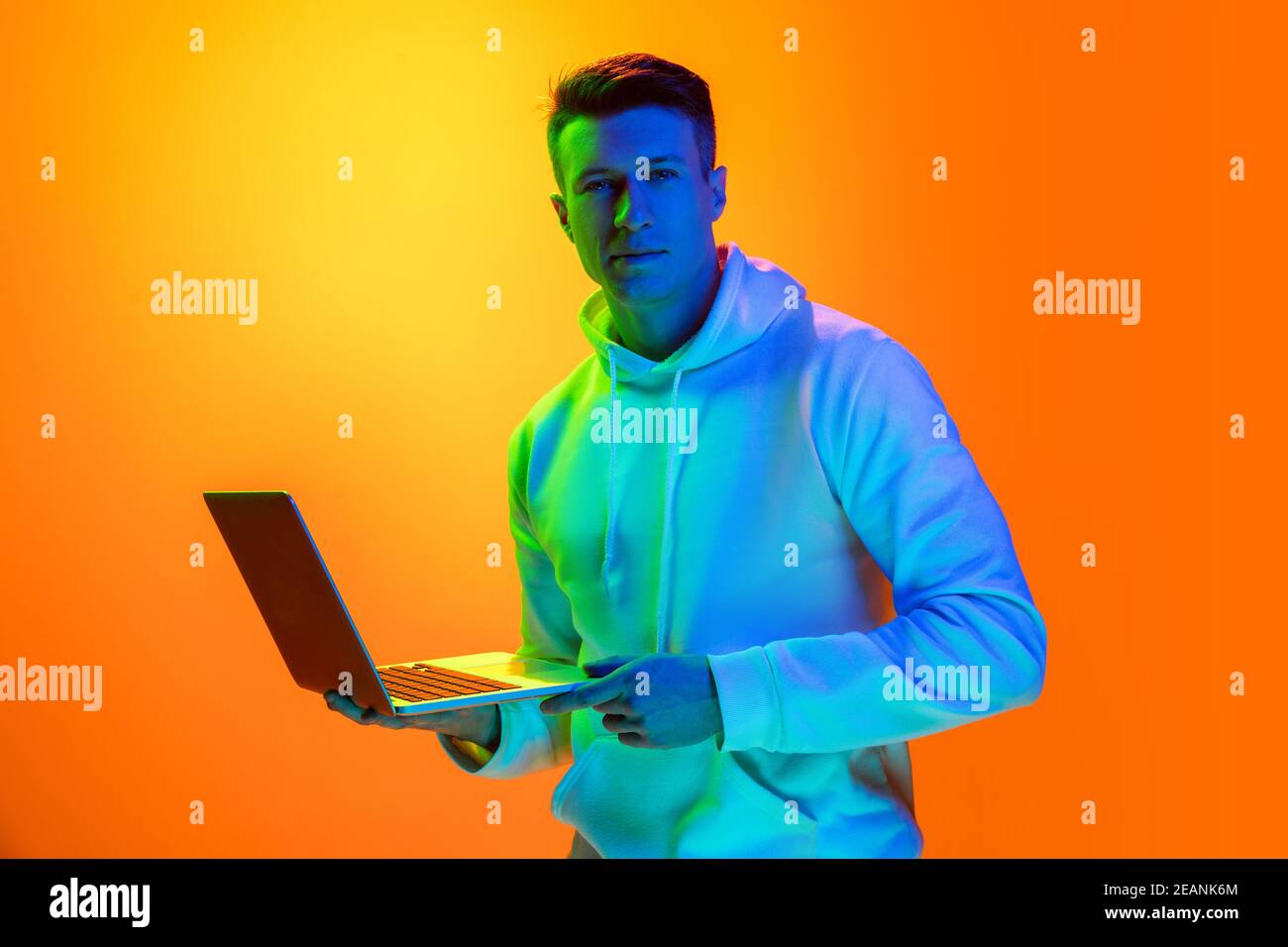 Scrolling laptop. Caucasian man's portrait isolated on yellow studio ...