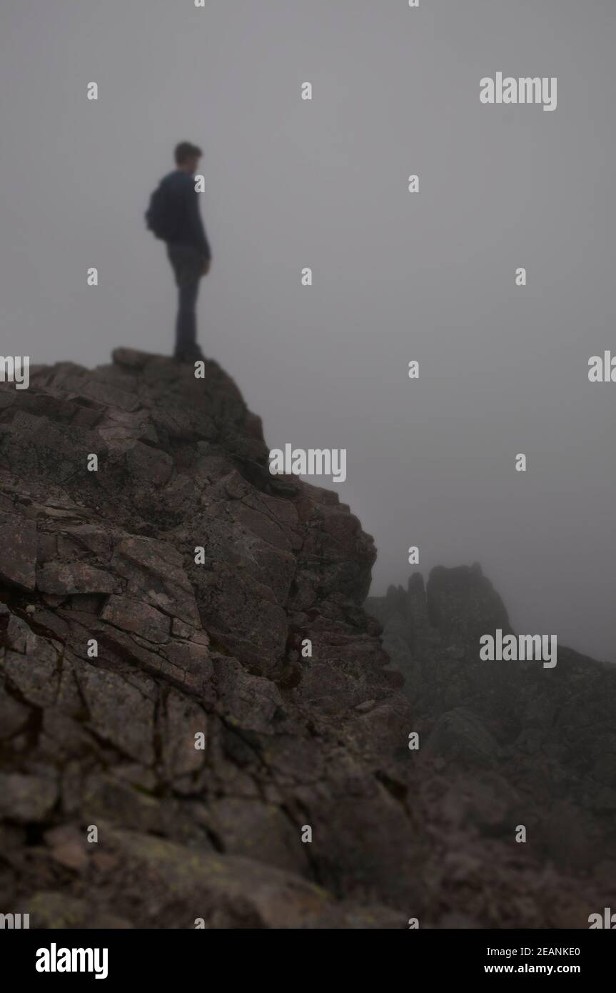 A manipulated photo of a young man on a cliff's edge in a desolate ...