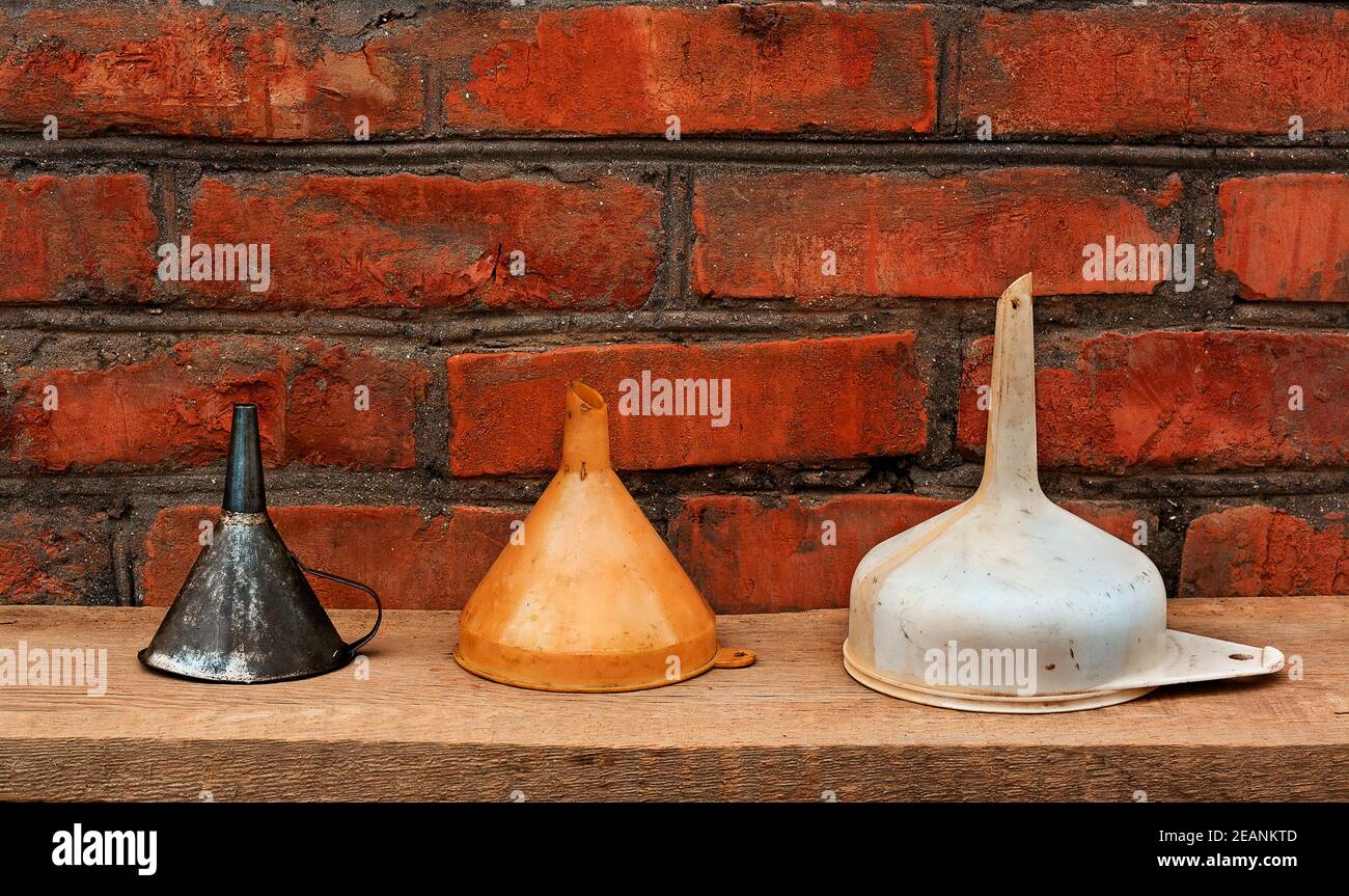 three old fashioned funnels from metal and plastic on rustic wooden ...