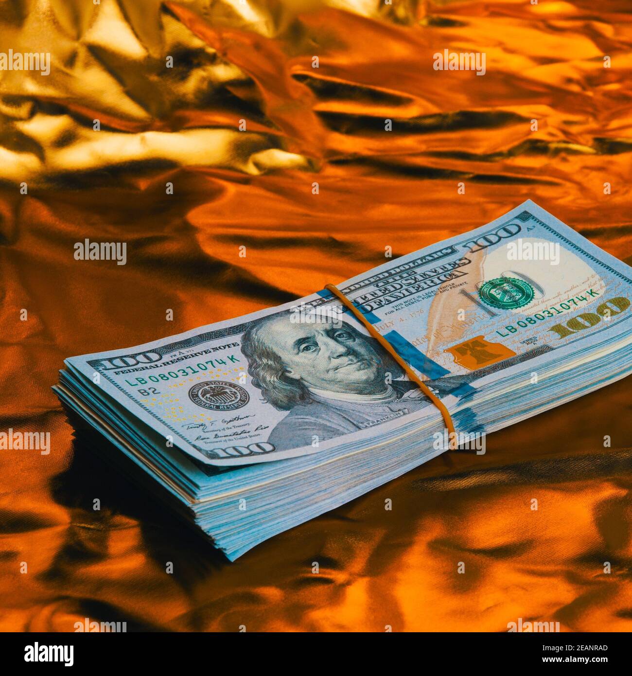 A large wad of dollars on a golden background Stock Photo - Alamy
