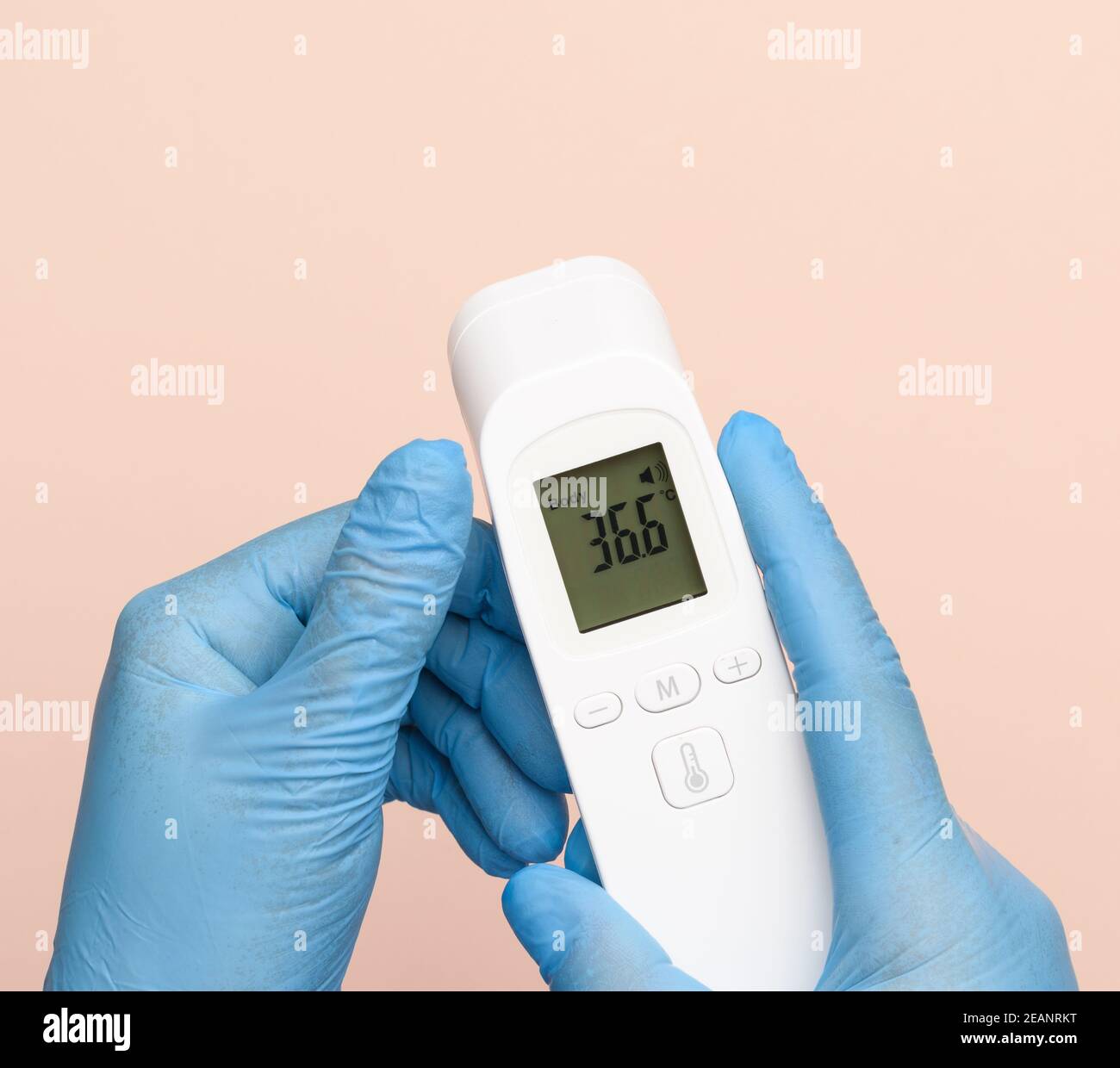 hand in blue latex gloves hold an electronic thermometer to measure ...