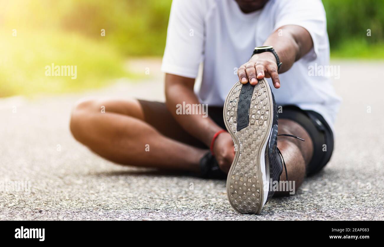 sport runner black man wear watch he sitting pull toe feet stretching ...