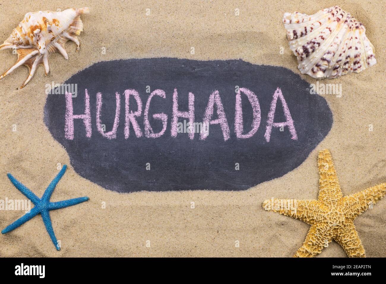 Handwritten word HURGHADA written in chalk, among seashells and ...