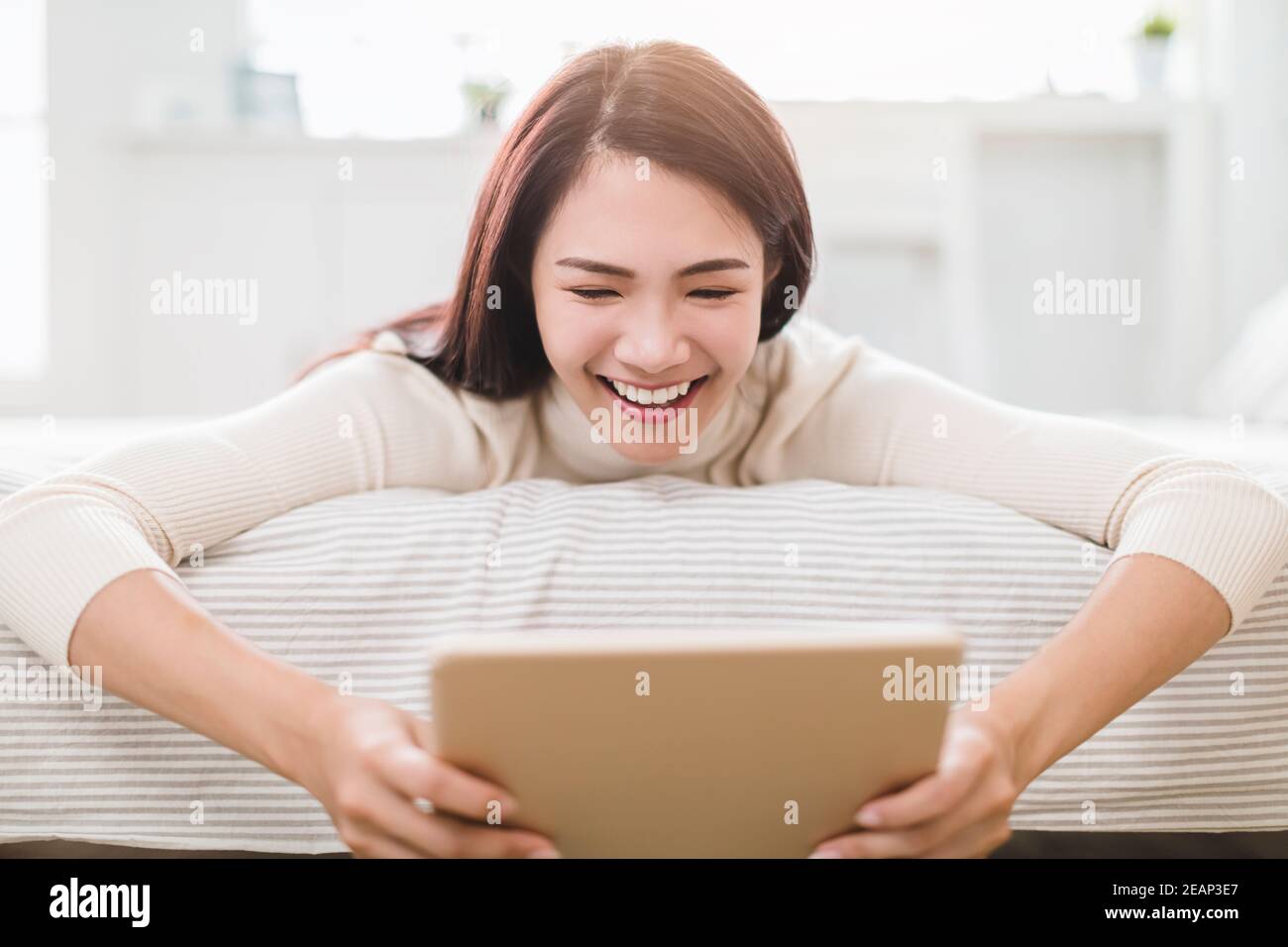 Smiling young woman looking tablet on bed Stock Photo - Alamy