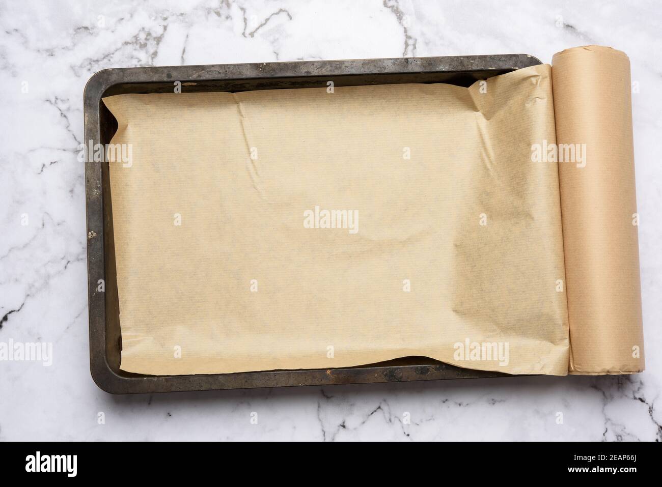 rectangular metal baking sheet and roll of brown parchment paper on ...
