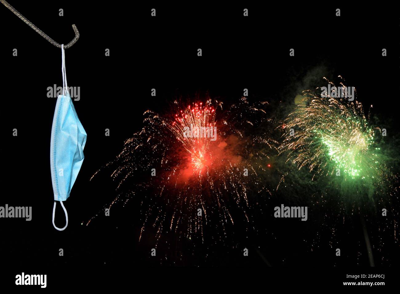 A protective breathing mask hangs on a hook with colorful fireworks ...