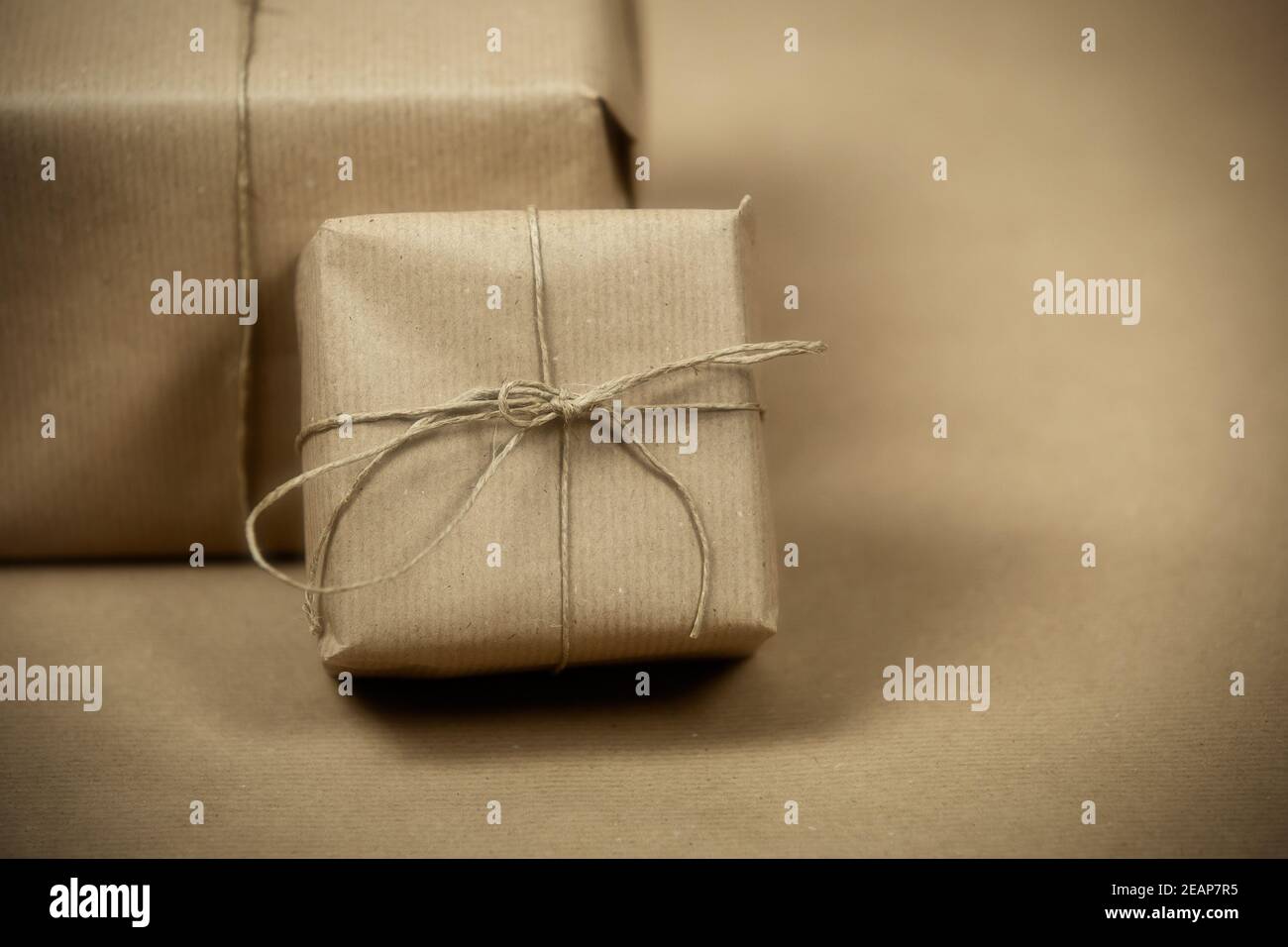 two gift package wrapped with plain brown paper and rope and brown ...
