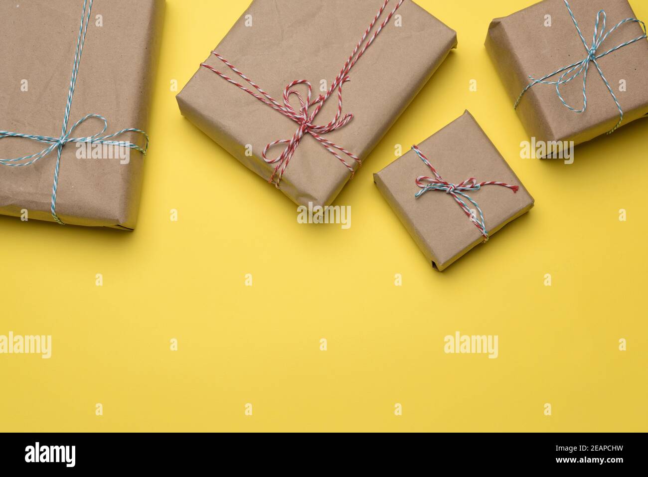 box wrapped in brown paper and tied with a rope, gift on a yellow ...