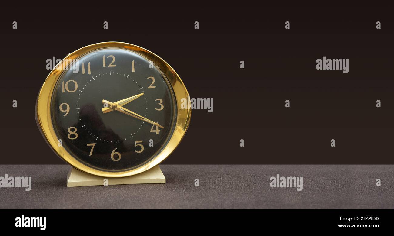Golden color table clock with gray background - time management concept ...
