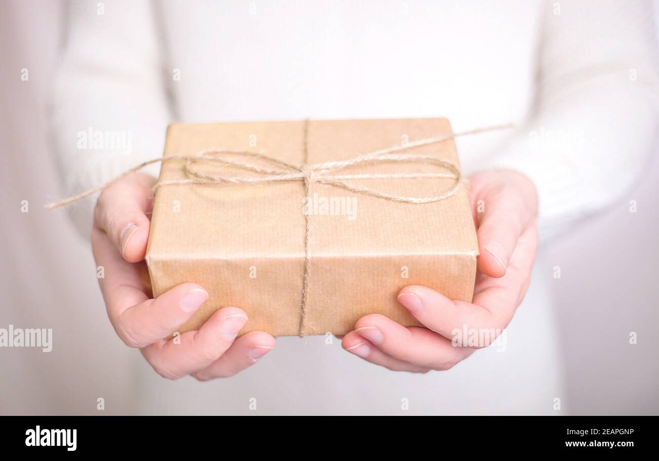 Woman holding a gift box in a gesture of giving Stock Photo - Alamy