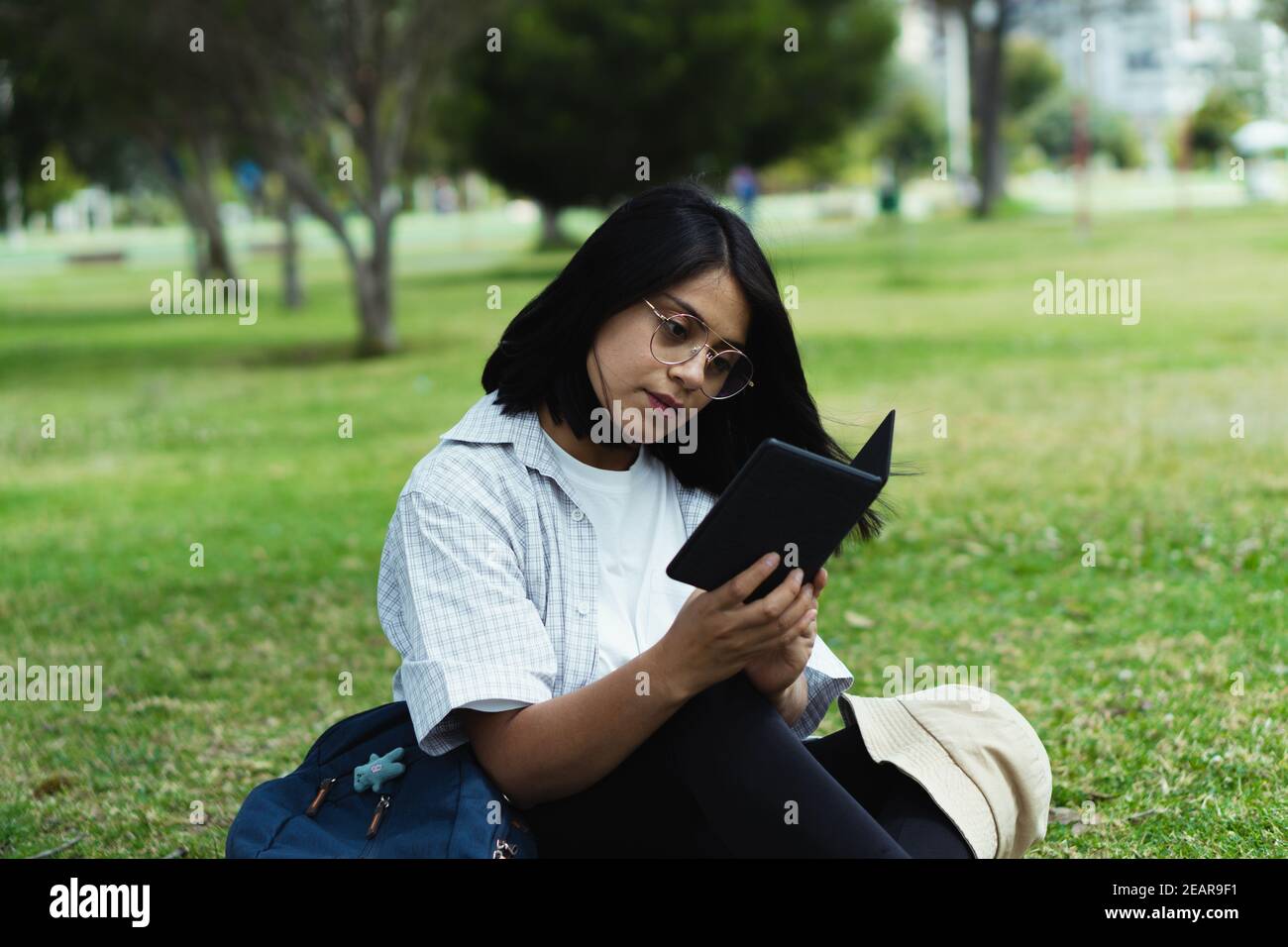 Beautiful college student in a time of rest and reading in the park ...