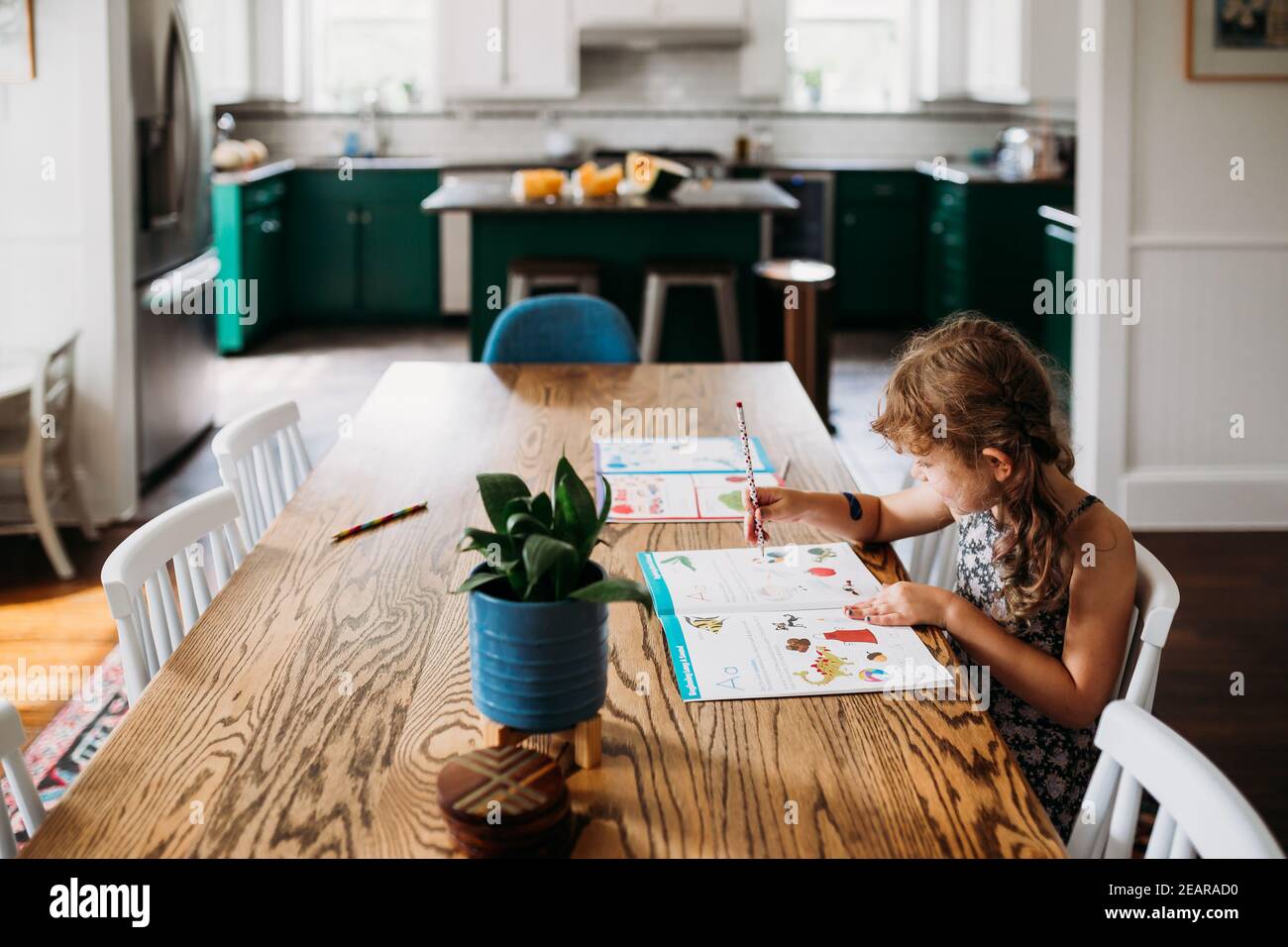 Young girl sitting at dining room table practicing school work Stock ...