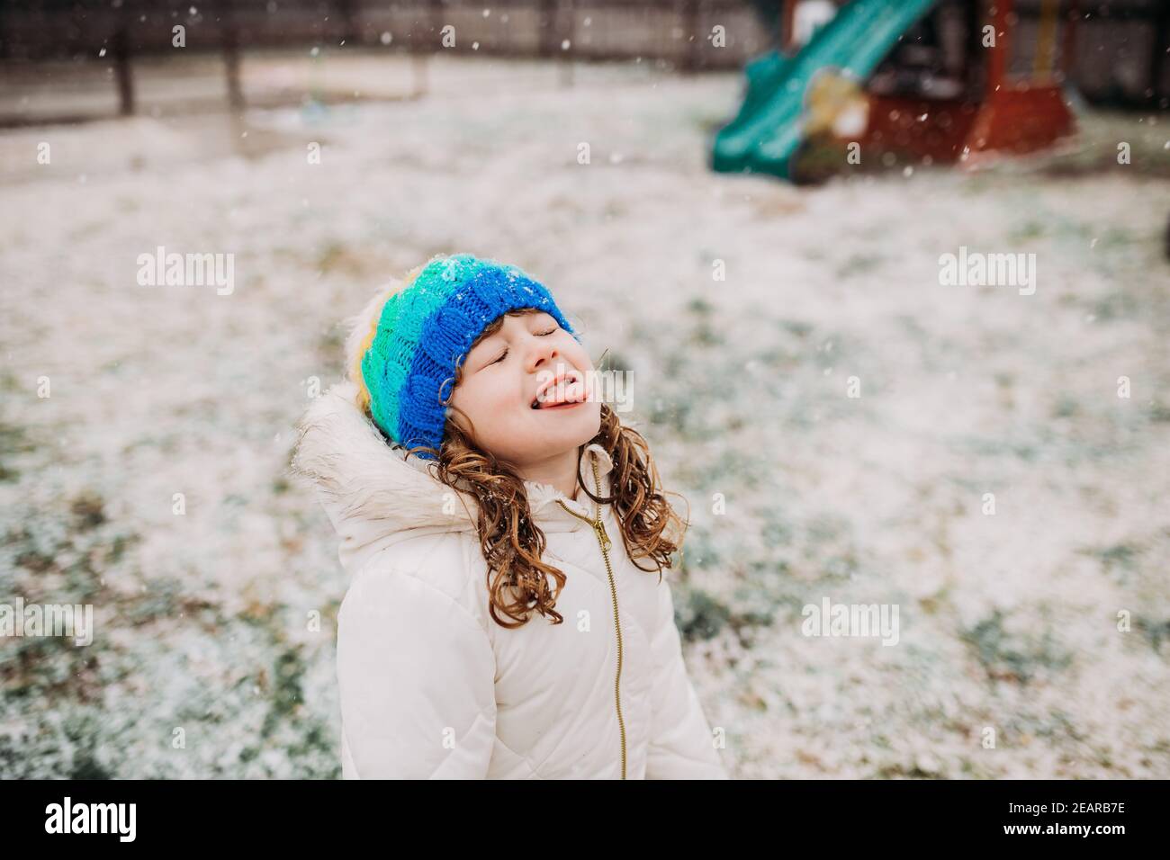 Young girl standing outside catching falling snow on tongue Stock Photo ...