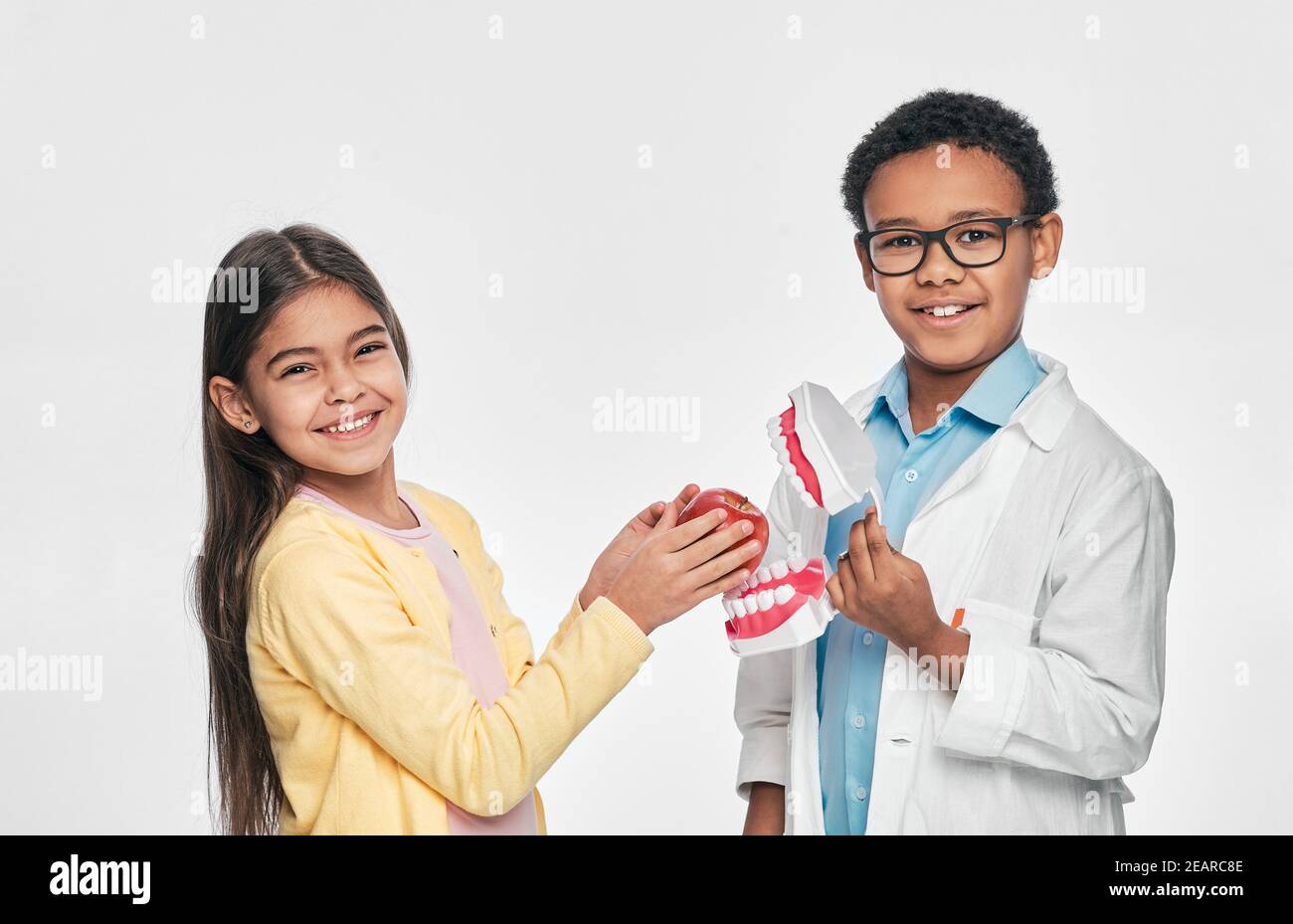 Child dental health. Funny boy and girl bites an apple using human ...