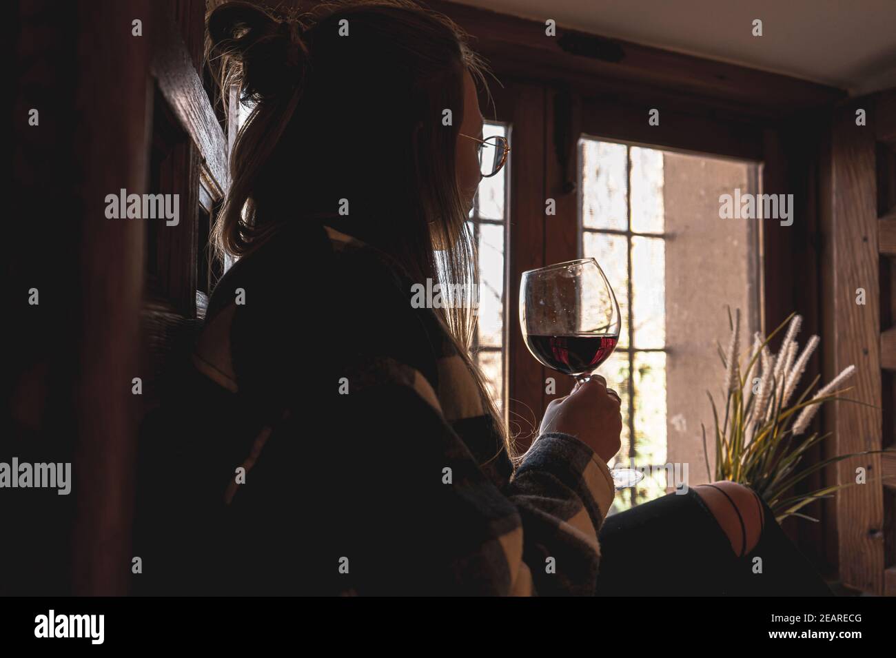 Relaxed woman at the window with glass of wine Stock Photo - Alamy
