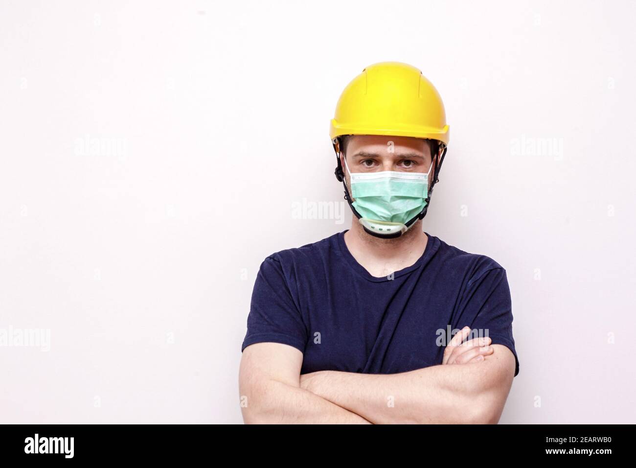 Caucasian construction worker wearing a face mask and yellow helmet ...