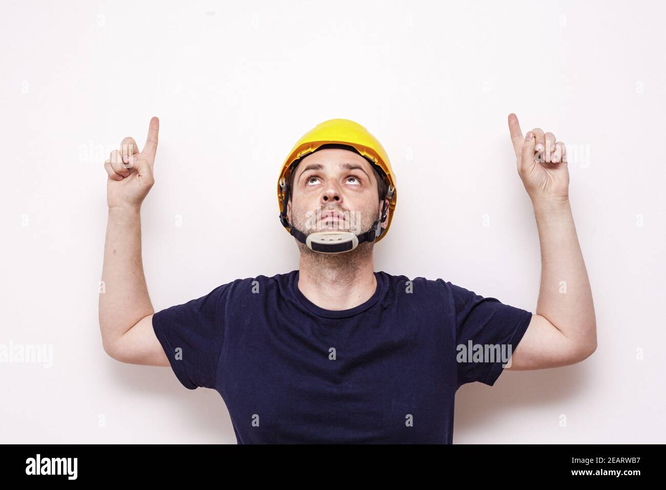 Caucasian worker wearing a yellow helmet and fingers pointing upward ...