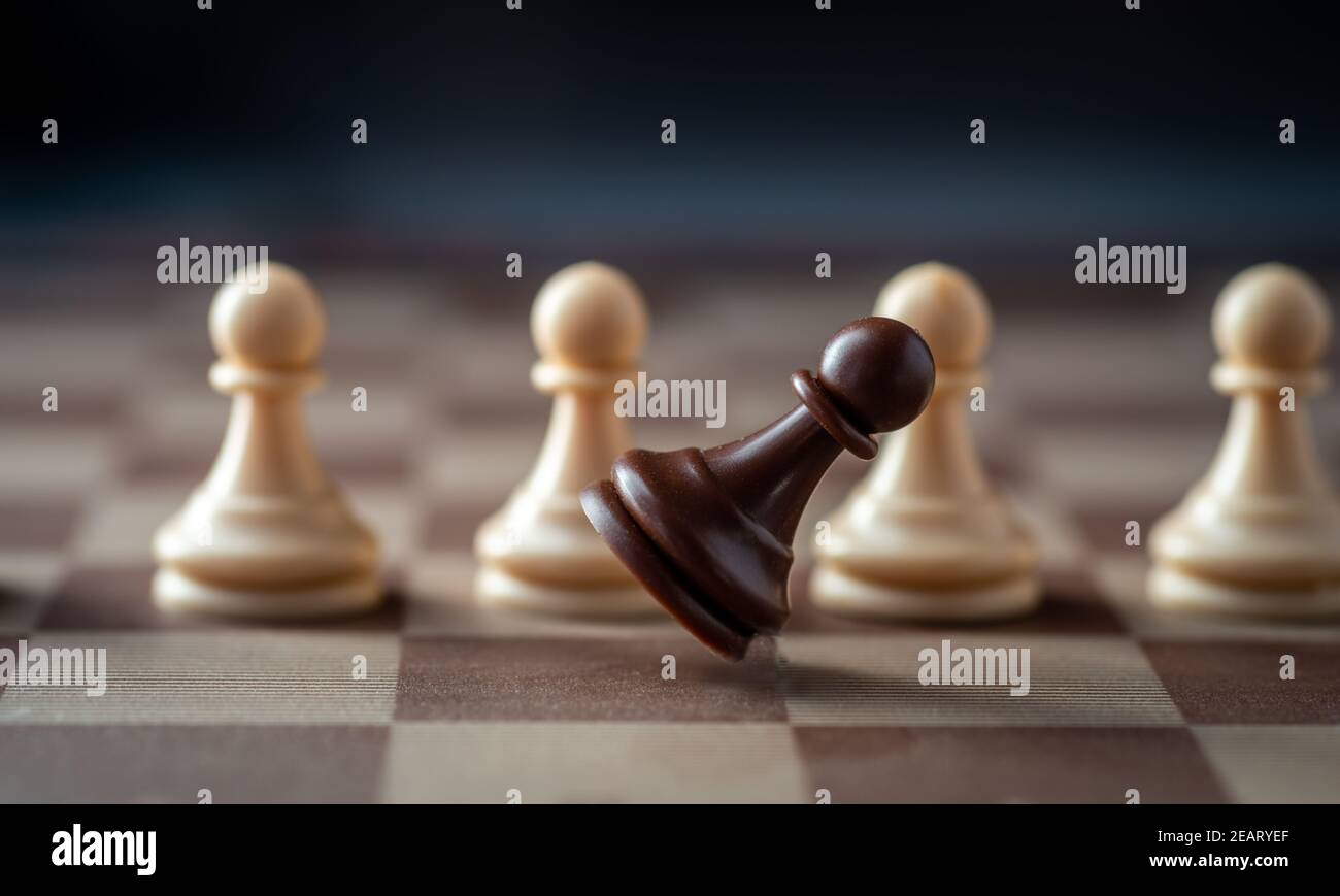 black chess pawn falling in front of white pieces. concept failing ...