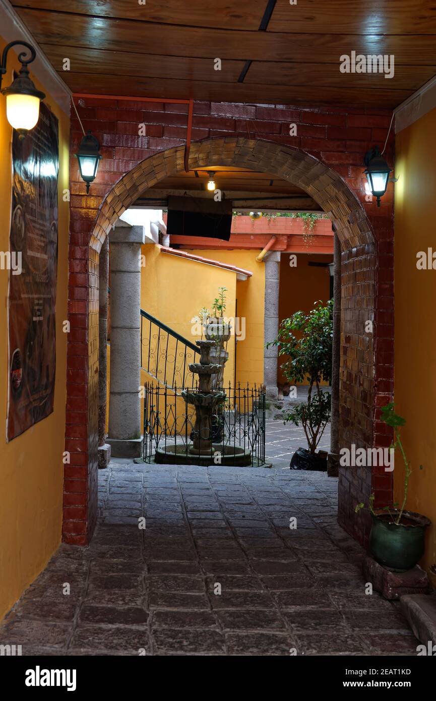 small courtyard, cobblestone, brick arch, fountain, lighted old hanging ...