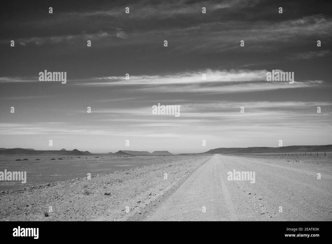 Long gravel empty road through barren desert Stock Photo - Alamy
