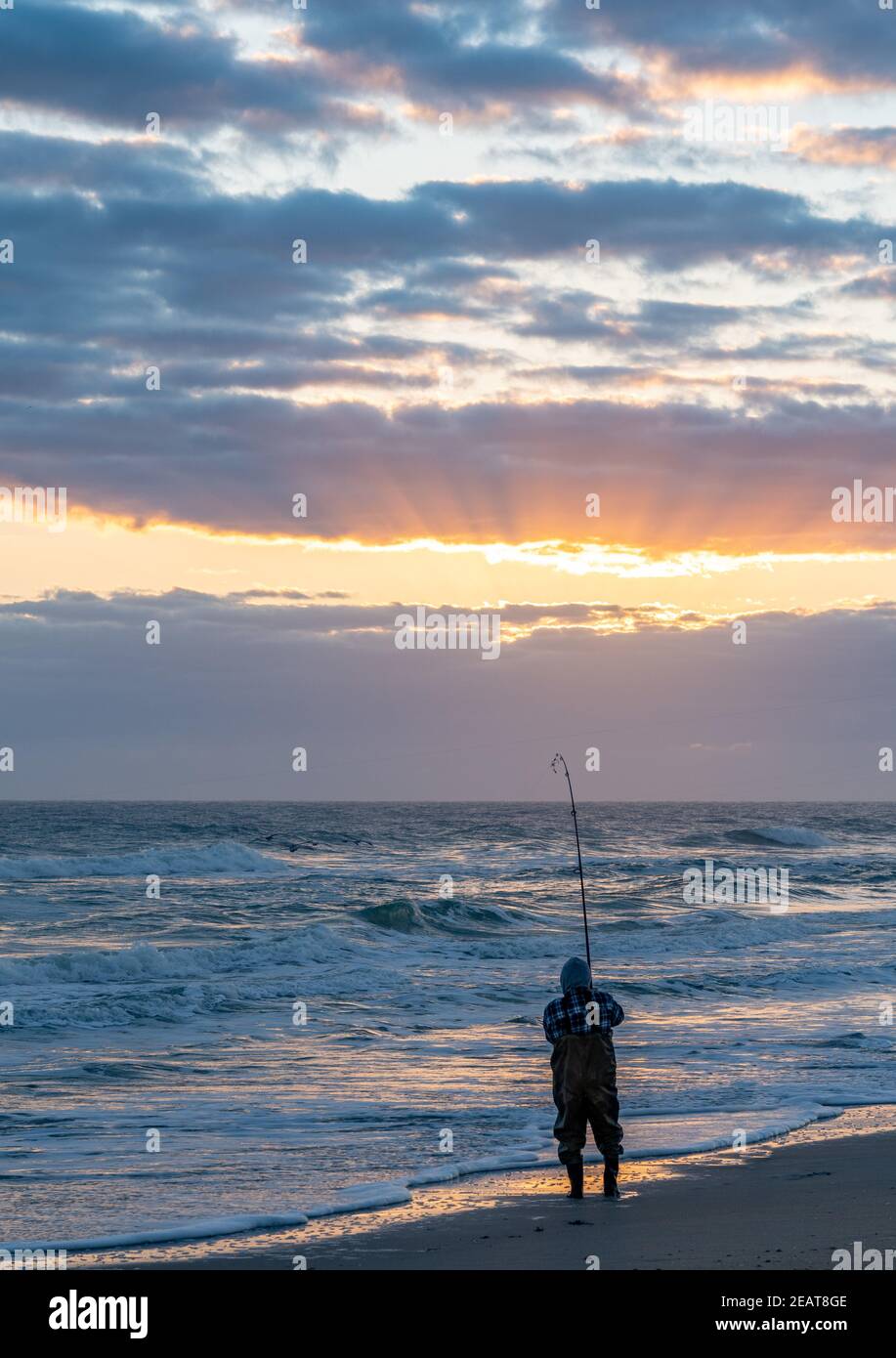 Vertical shot of a male fishing during sunrise Stock Photo - Alamy