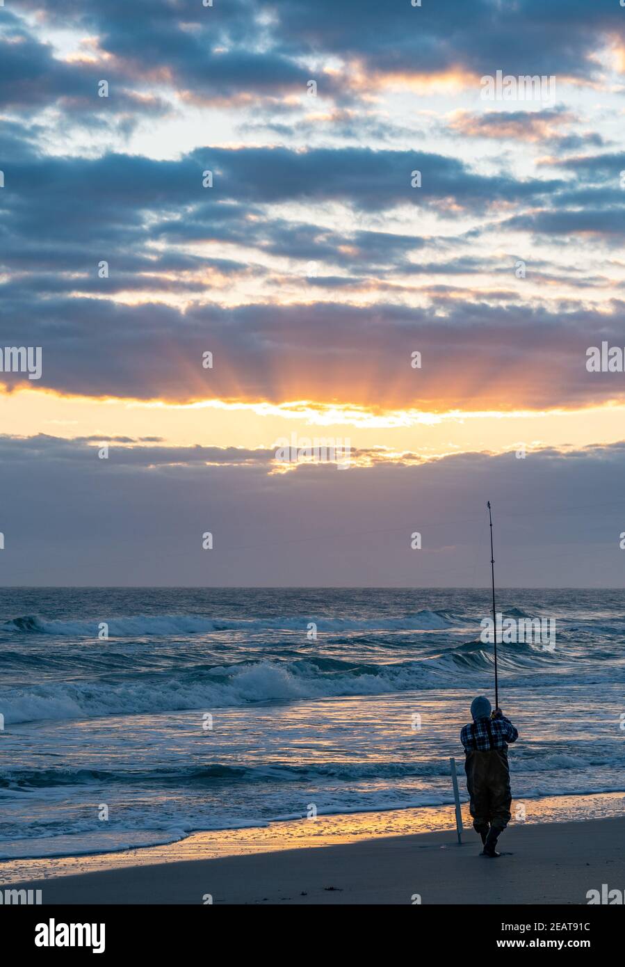 Vertical shot of a male fishing during sunrise Stock Photo - Alamy