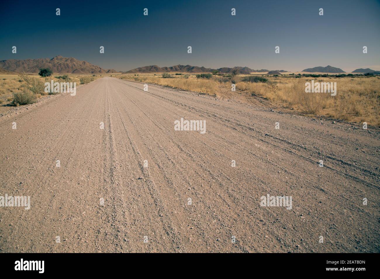 Long gravel empty road through barren desert Stock Photo - Alamy