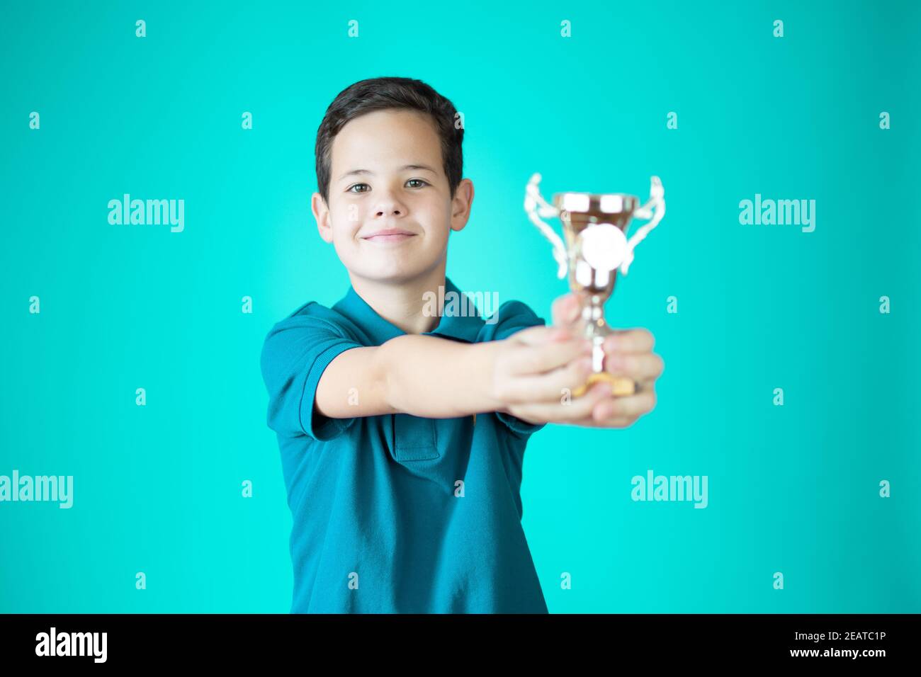 young boy holding a trophy with celebrating pose over green background ...