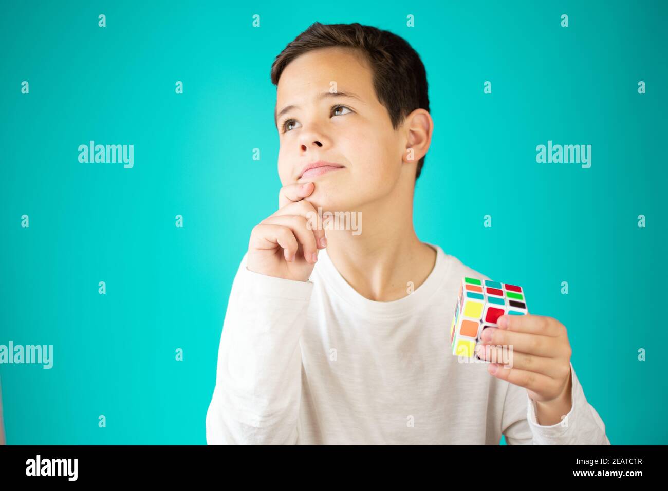 Young boy pensive plays with rubik's cube over green background Stock ...