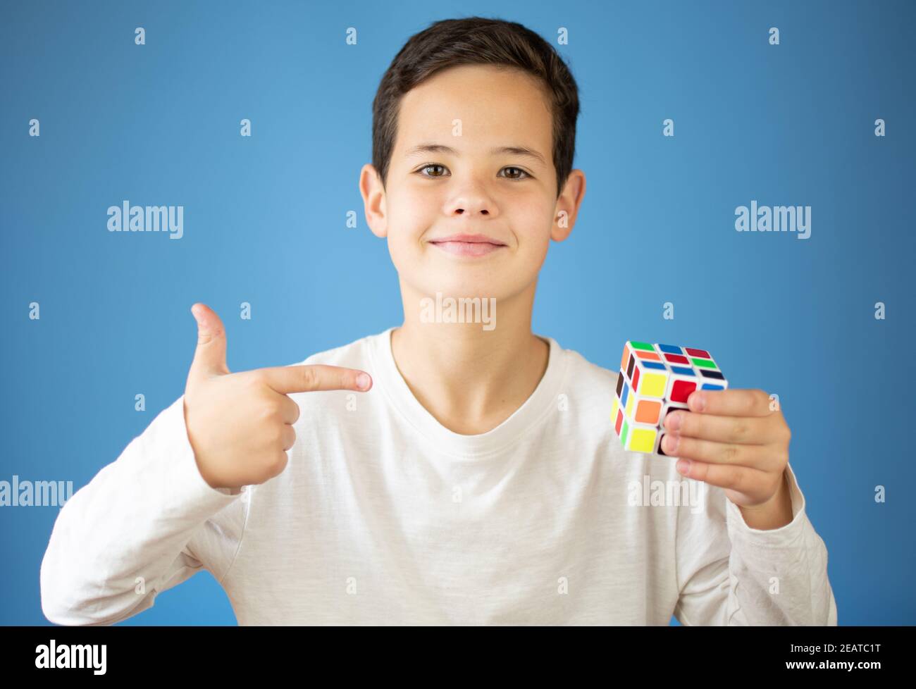Young boy plays with rubik's cube over blue background Stock Photo - Alamy